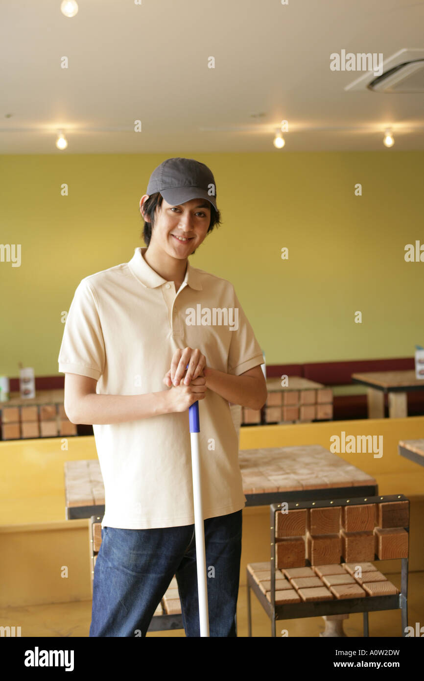 Portrait of a waiter holding a mop and smiling Stock Photo - Alamy