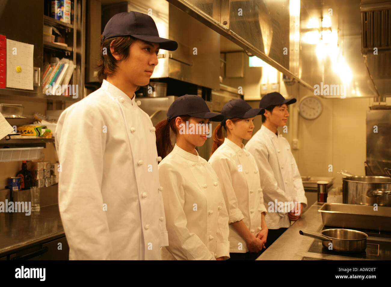 Side profile of two male chefs and two female chefs standing side by ...