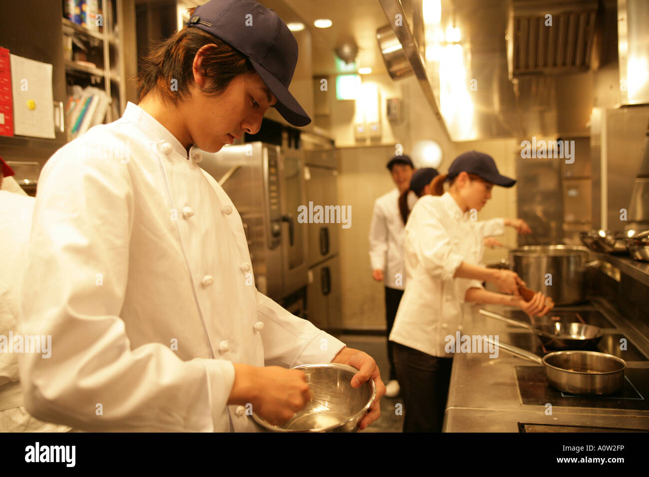 Side profile of a male chef and his colleagues in the kitchen Stock ...