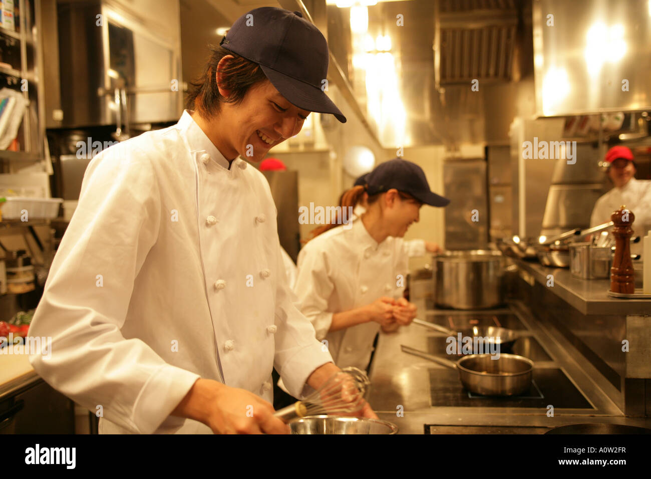 Male chef and his colleagues working in the kitchen and smiling Stock ...