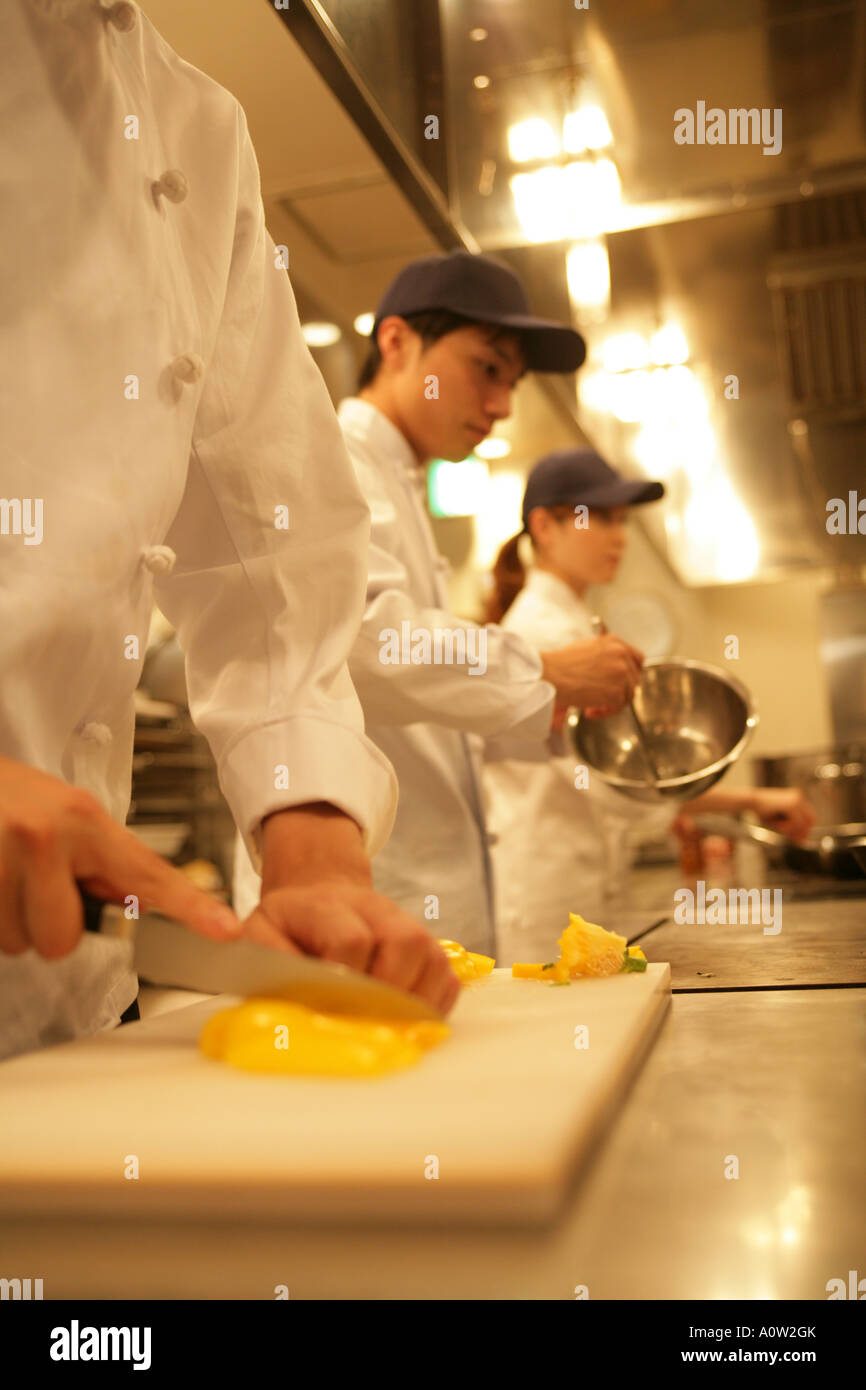 Two male chefs and a female chef preparing food in the kitchen Stock ...