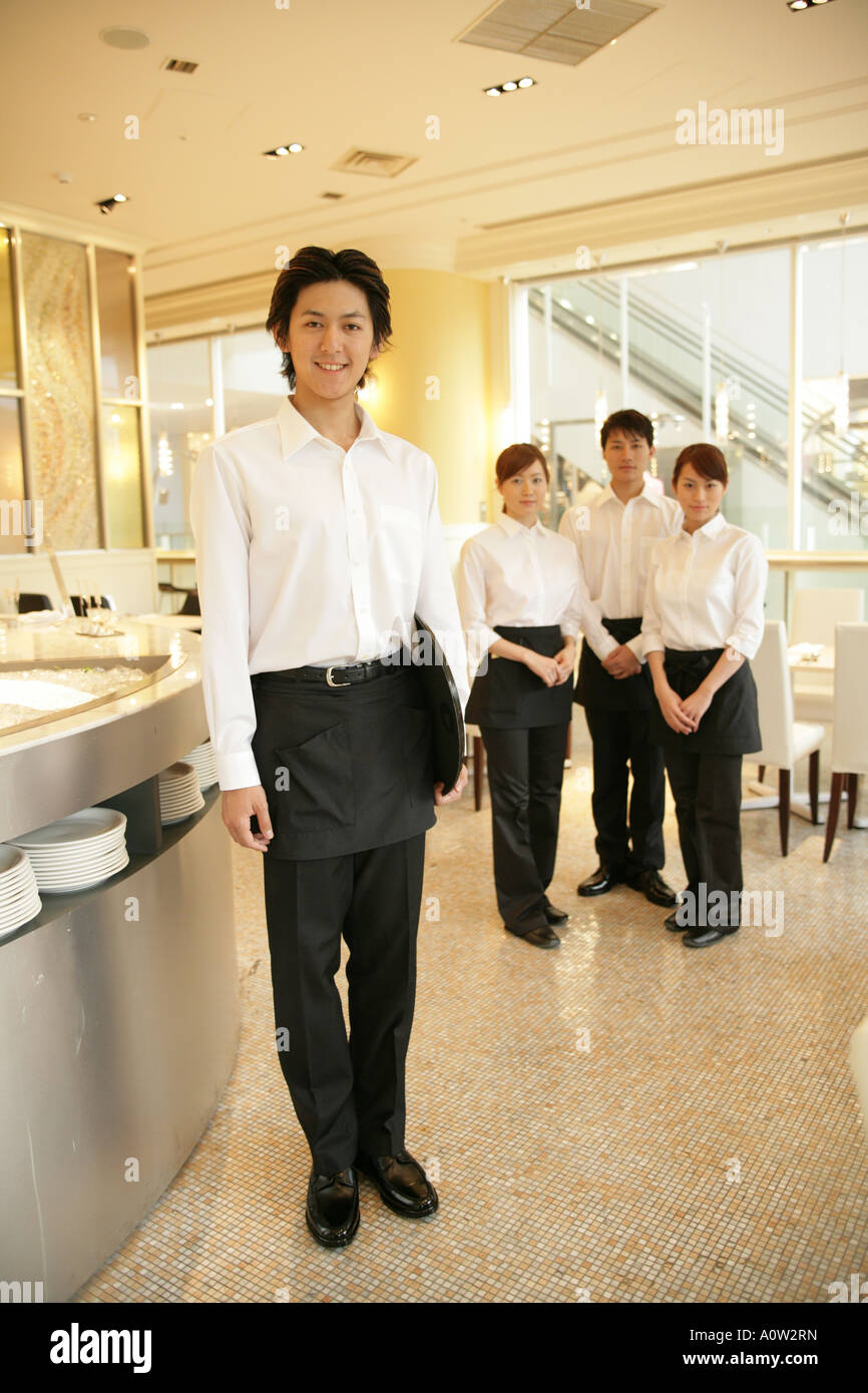 Portrait of two waiters and two waitresses standing in a restaurant ...
