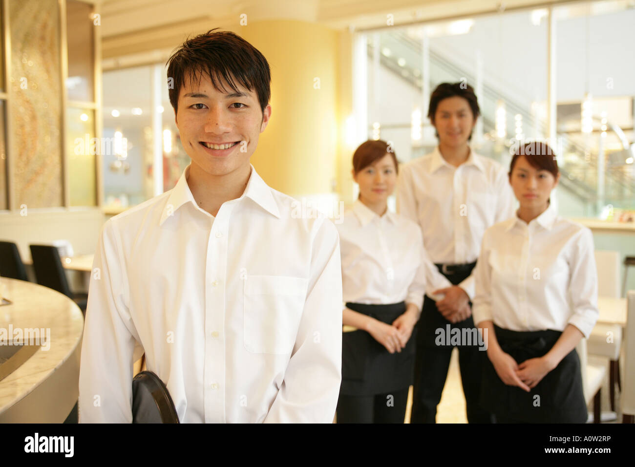 Portrait of two waiters and two waitresses standing in a restaurant ...