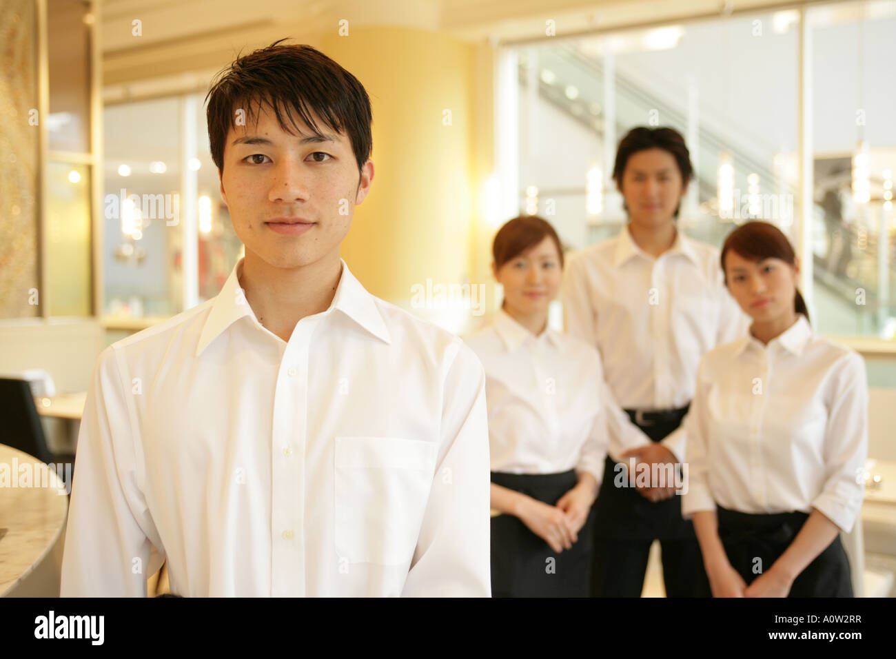 Portrait of two waiters and two waitresses standing in a restaurant ...