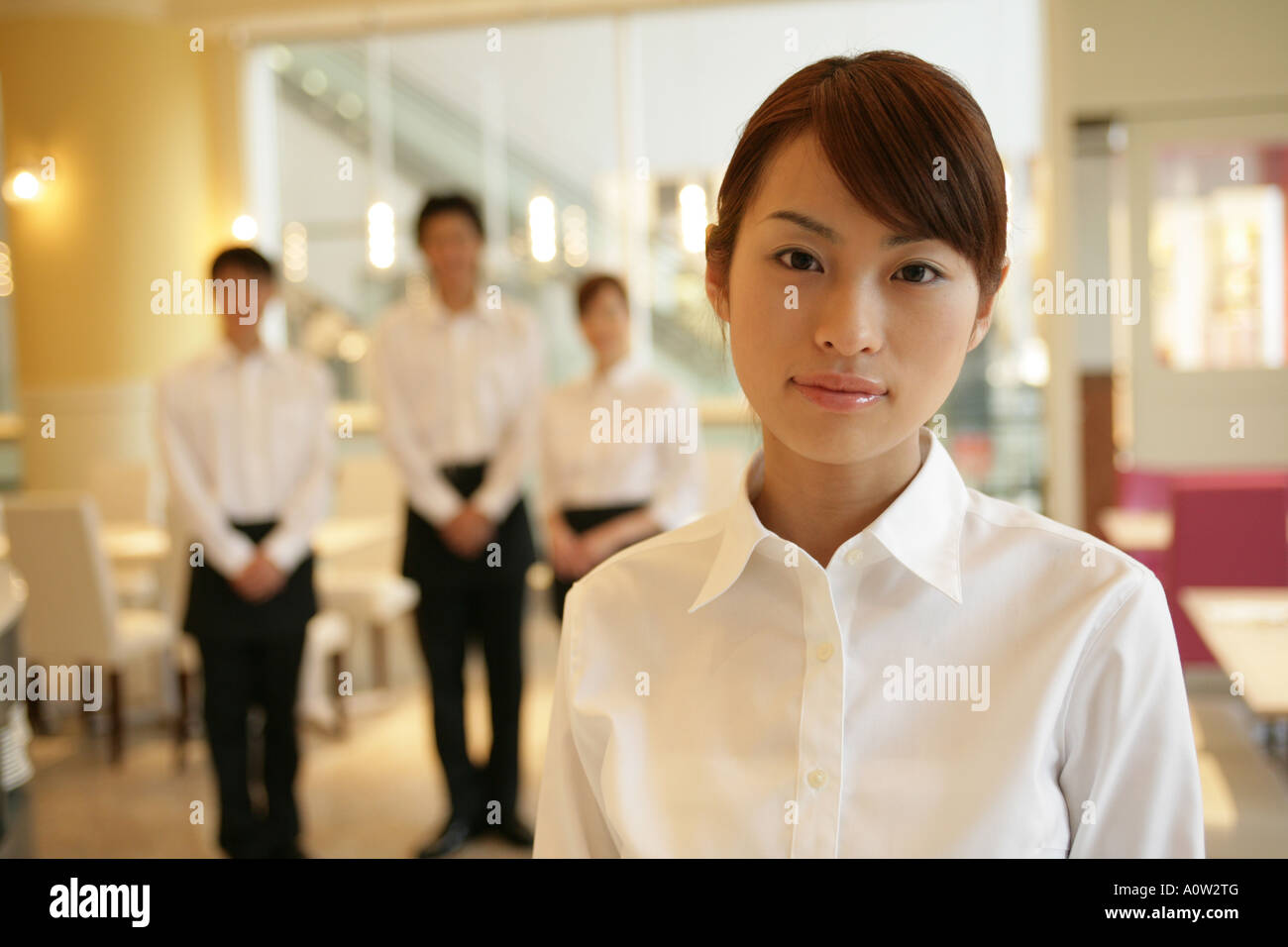 Portrait of two waiters and two waitresses standing in a restaurant ...