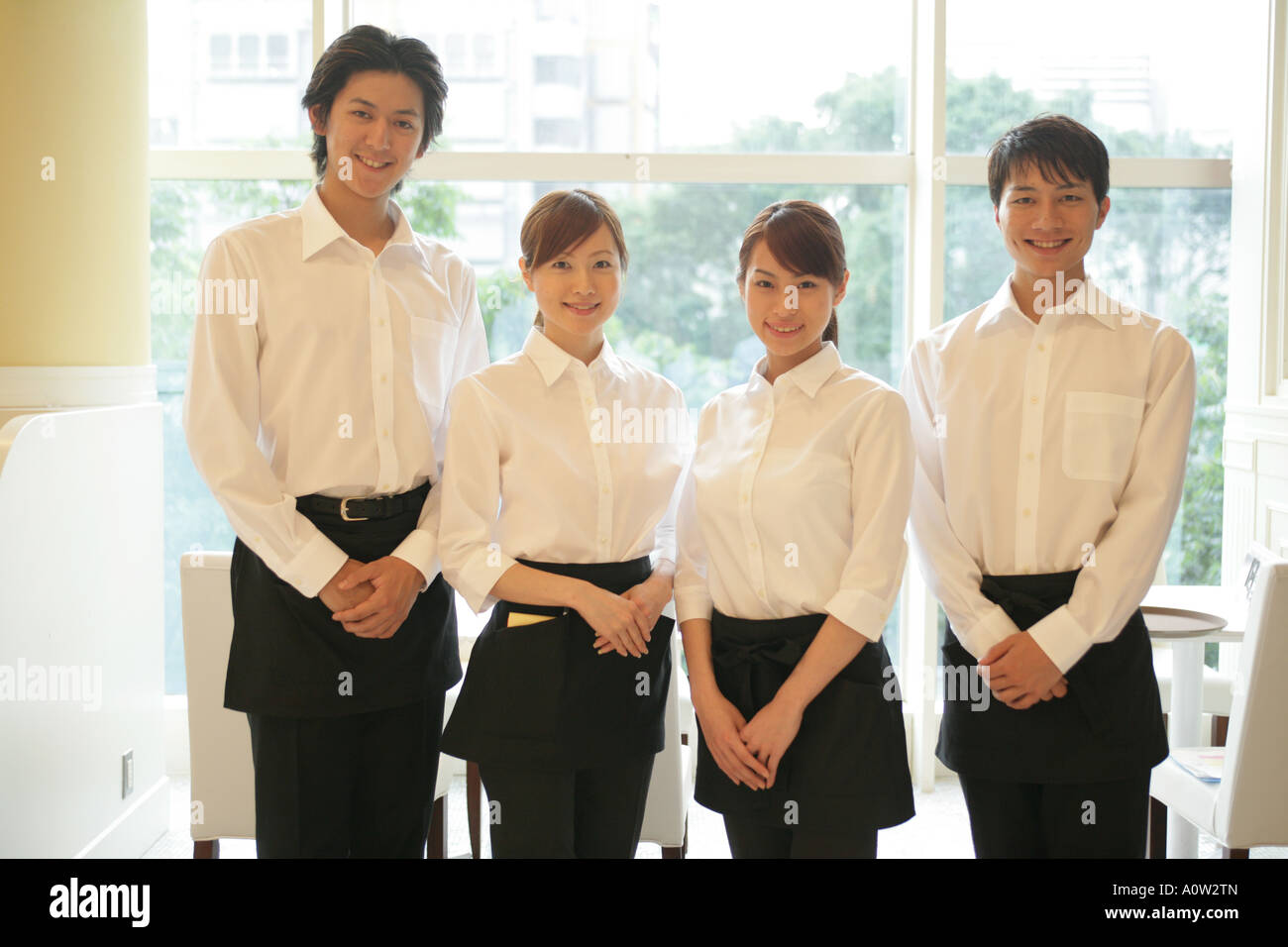 Portrait of two waiters and two waitresses standing in a restaurant ...