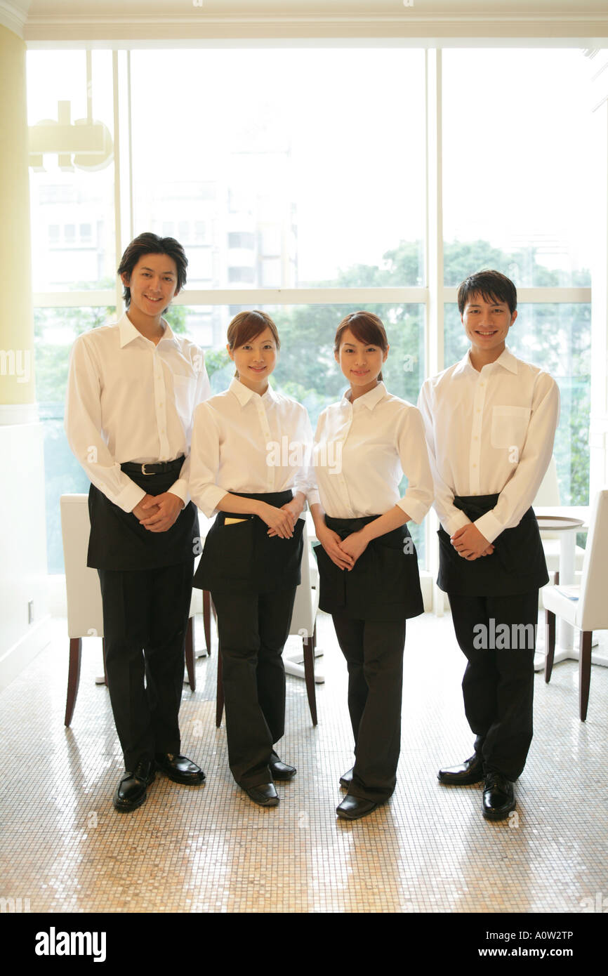 Portrait of two waiters and two waitresses standing in a restaurant ...
