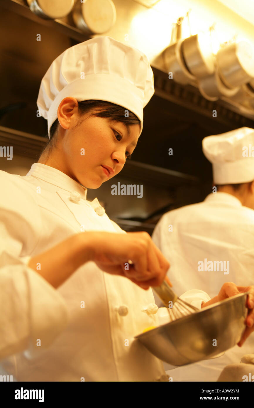 Low angle view of a female chef holding a wire whisk with a mixing bowl ...