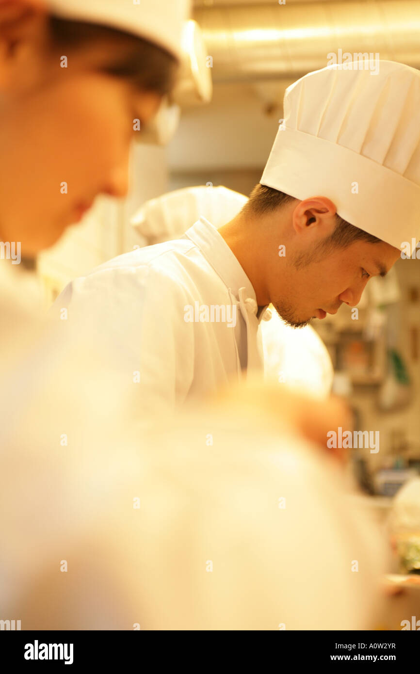 Side profile of a male chef and his colleagues in the kitchen Stock ...