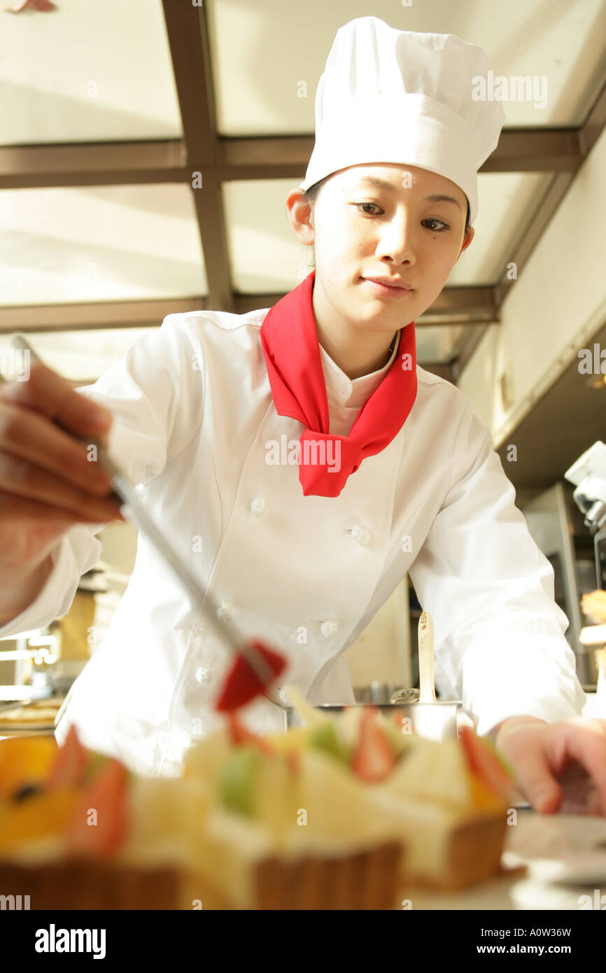 Female chef decorating a tart with a slice of strawberry Stock Photo ...