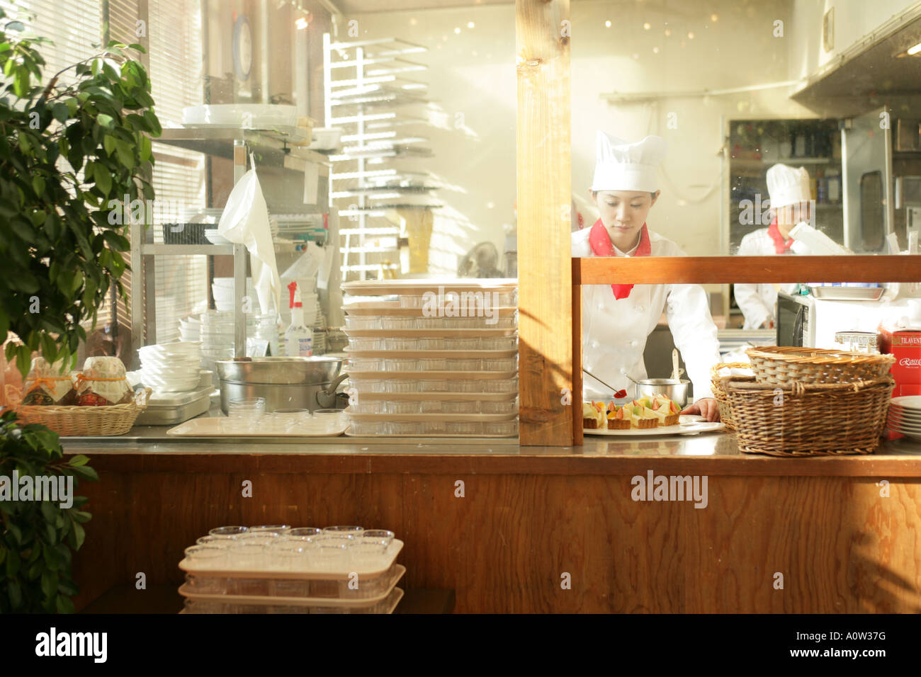 Female chef decorating a tart with a slice of strawberry and a chef ...
