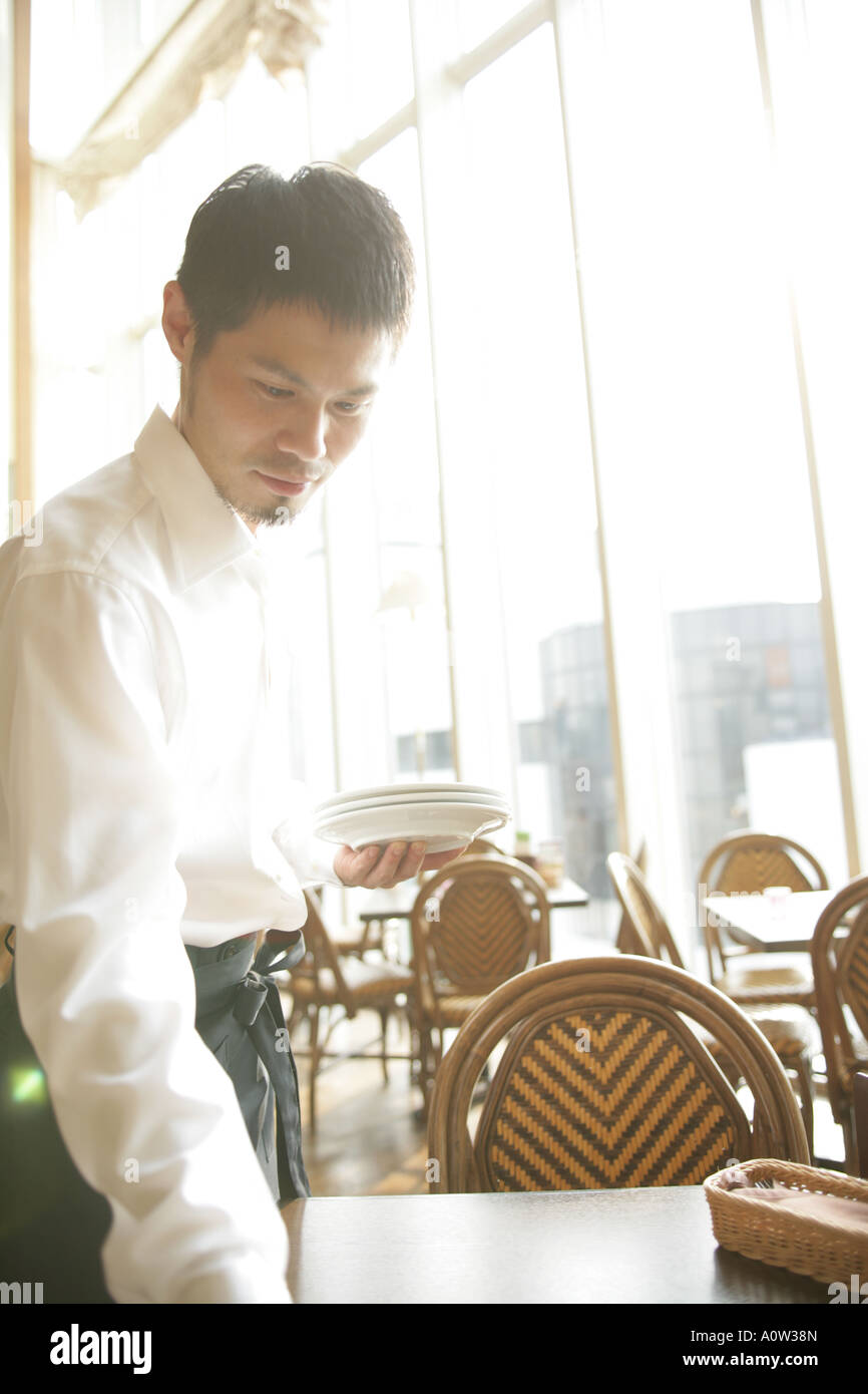 Side profile of a waiter putting plates on the table Stock Photo - Alamy
