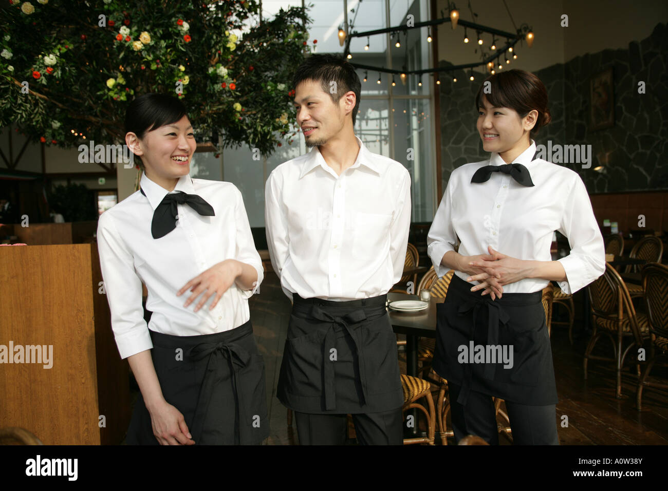 Two waitresses with a waiter standing in a restaurant and smiling Stock ...
