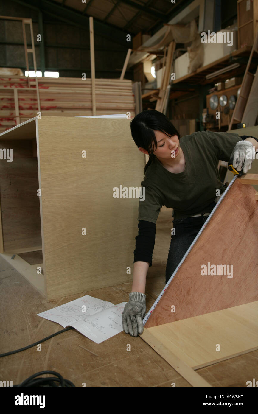 Young woman measuring sheet of plywood with tape measure Stock Photo ...
