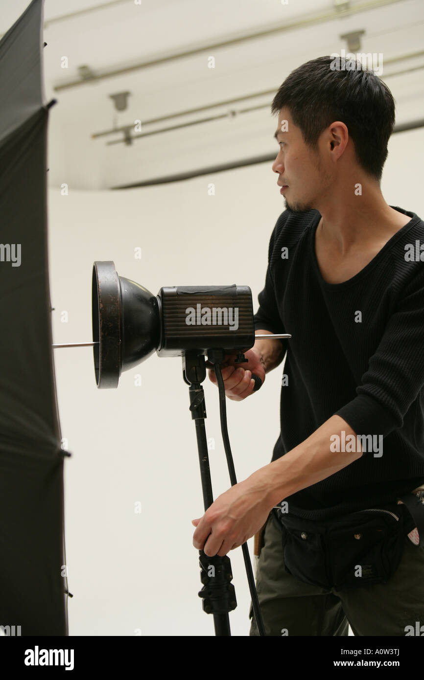 Close up of a young man adjusting lighting equipment in a film studio ...