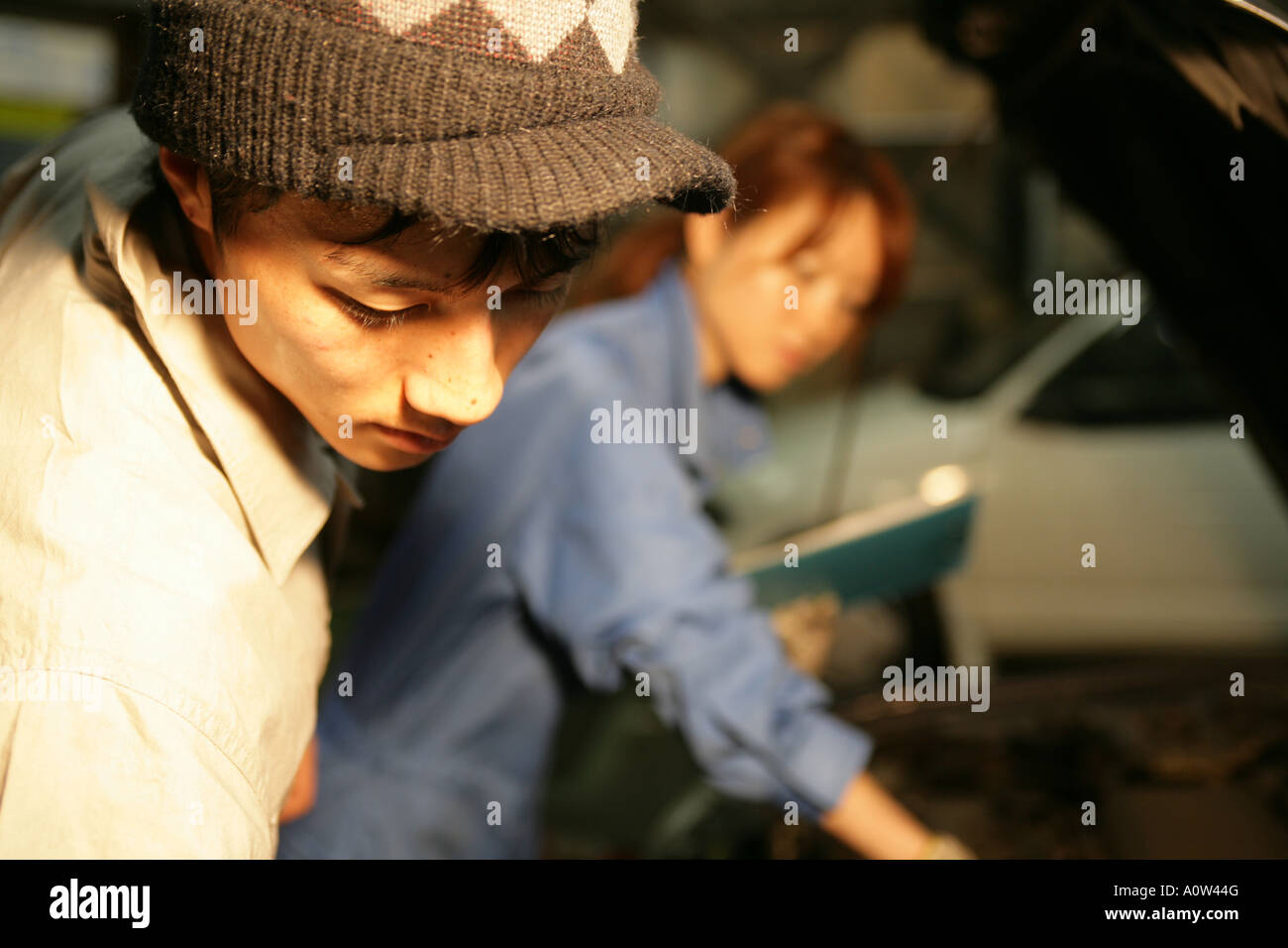 Close up of an auto mechanic looking down with a female mechanic in the ...
