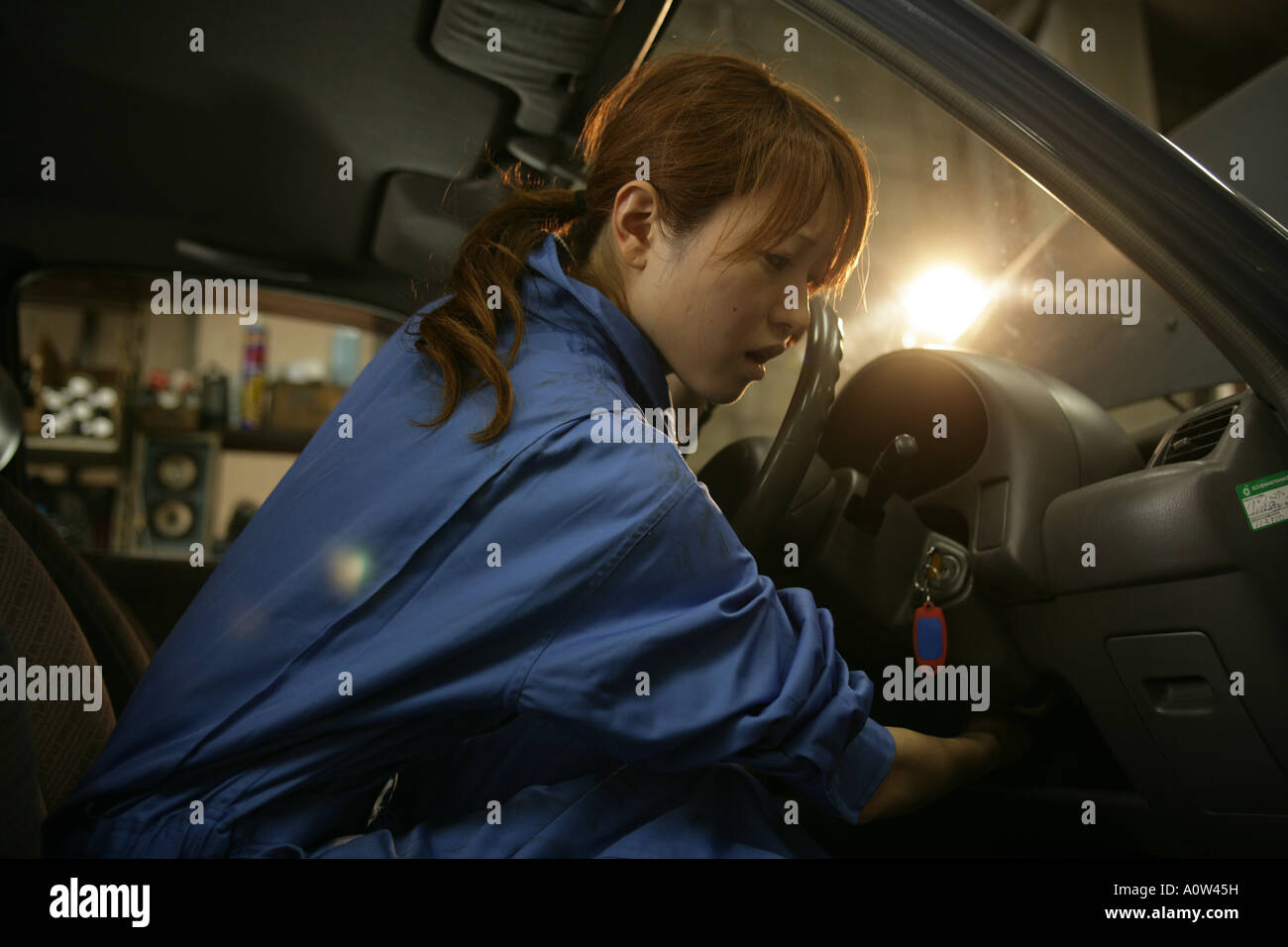 Side profile of a female auto mechanic examining a car Stock Photo - Alamy