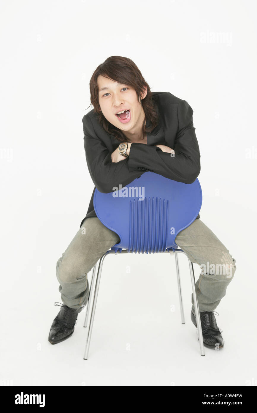Portrait of a young man sitting on a chair and posing Stock Photo - Alamy