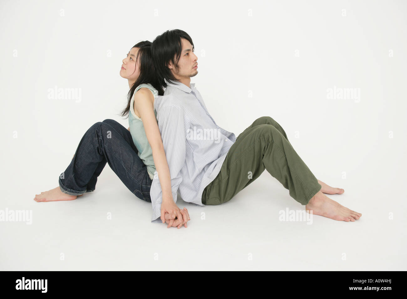 Side profile of a young couple sitting back to back Stock Photo - Alamy