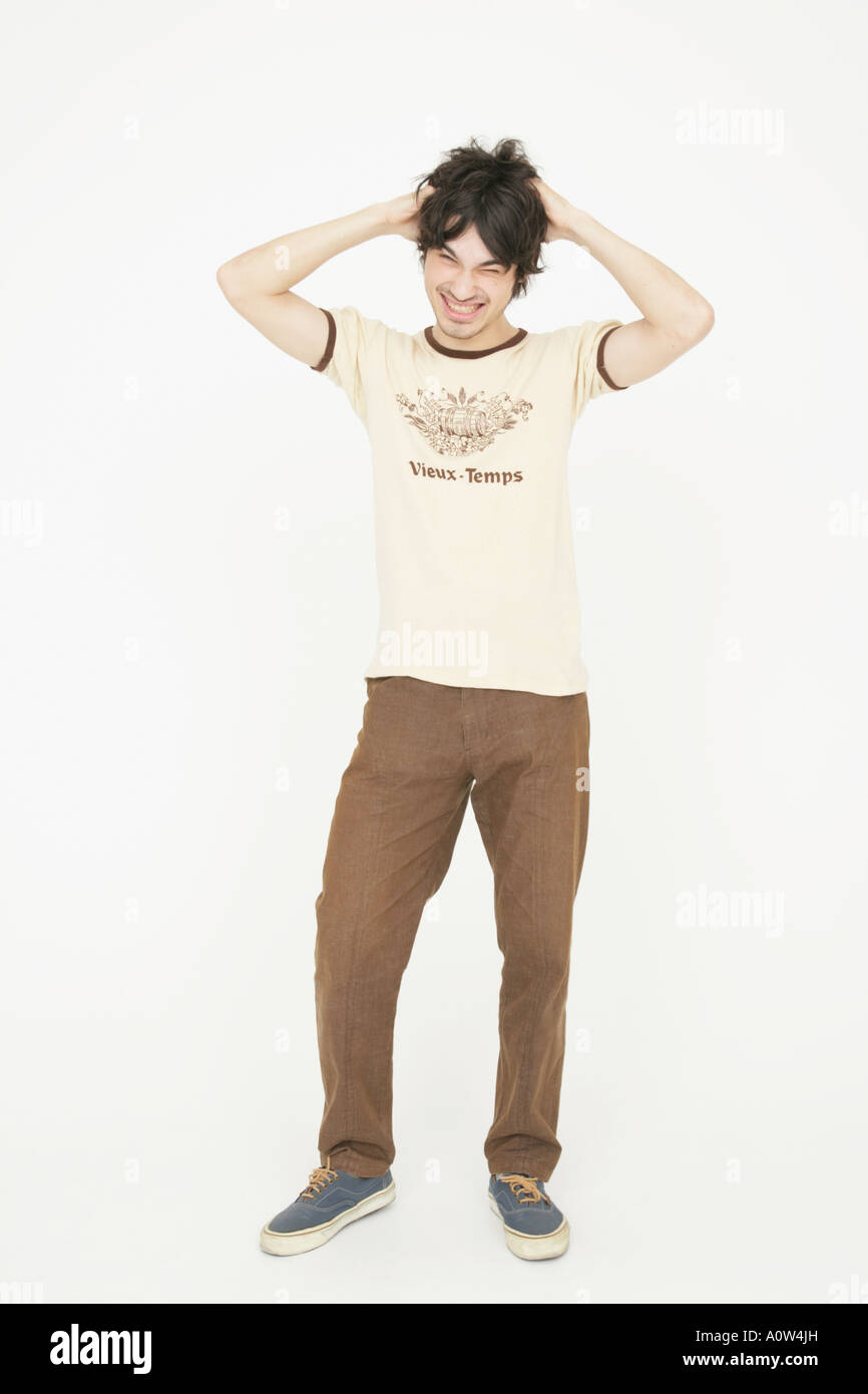 Young man tousling his hair and smiling Stock Photo - Alamy