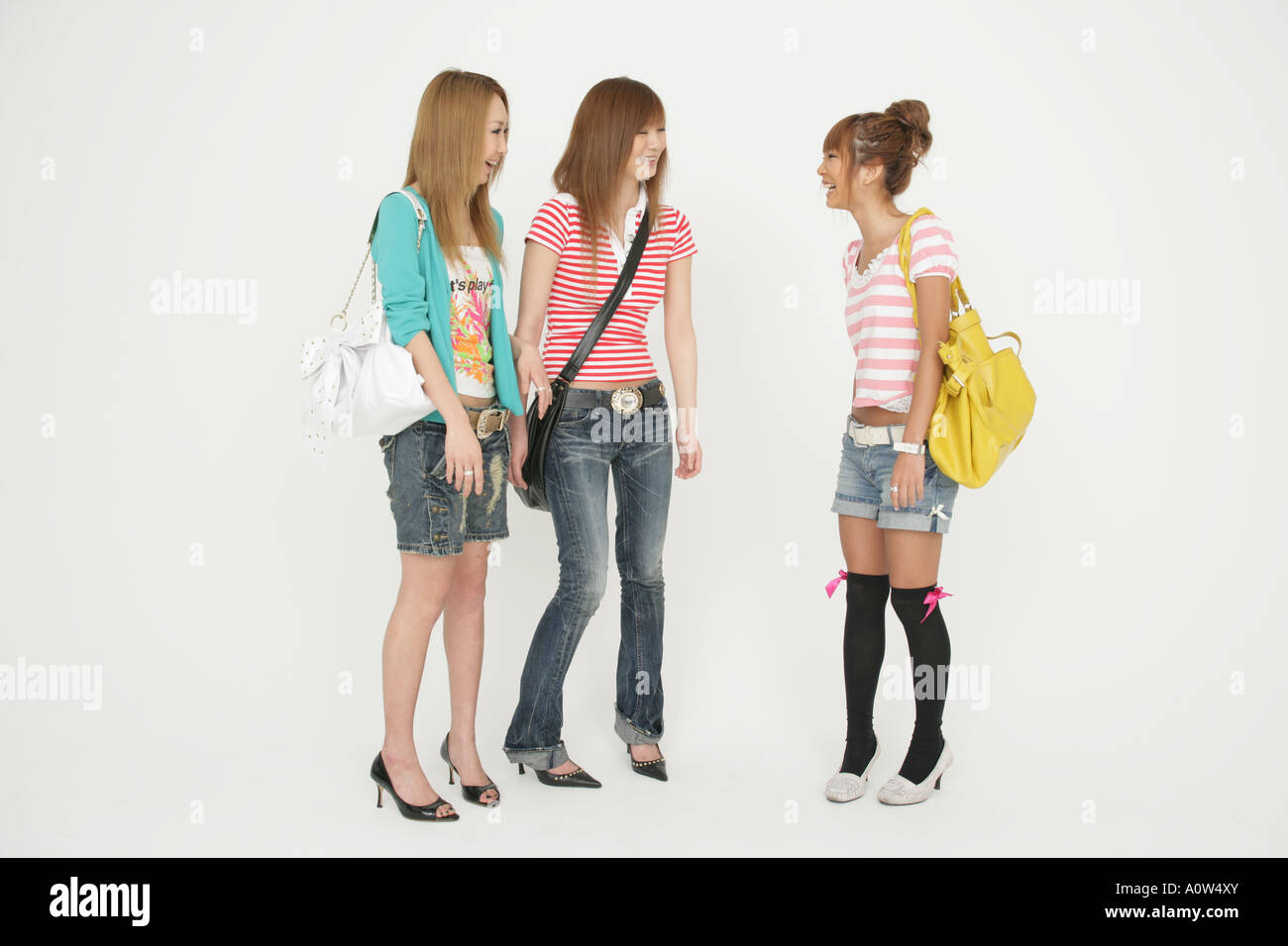 Three young women carrying hand bags and smiling Stock Photo - Alamy