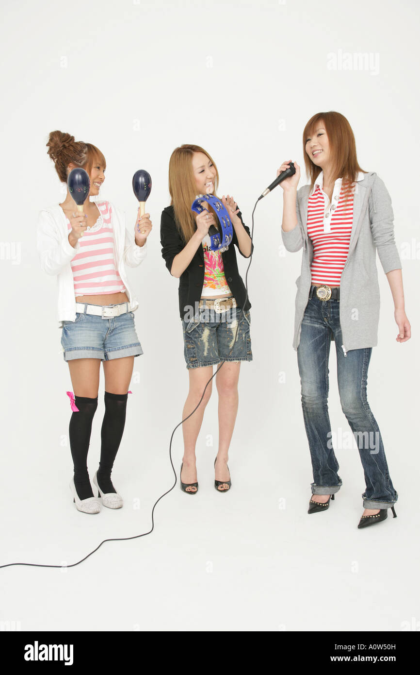 Young woman singing with another two young women playing musical ...