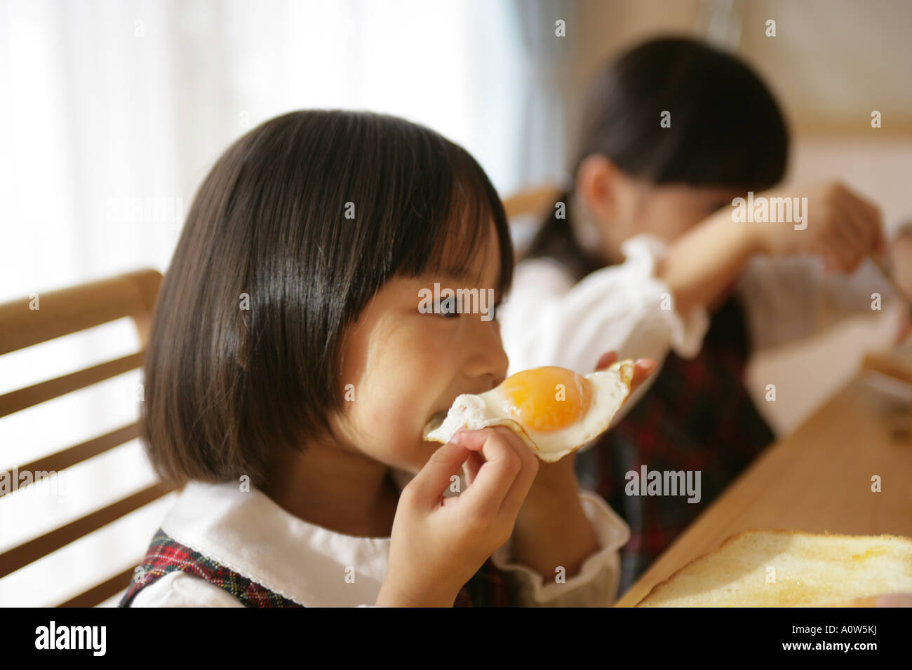 Two girls having breakfast at the dining table Stock Photo - Alamy