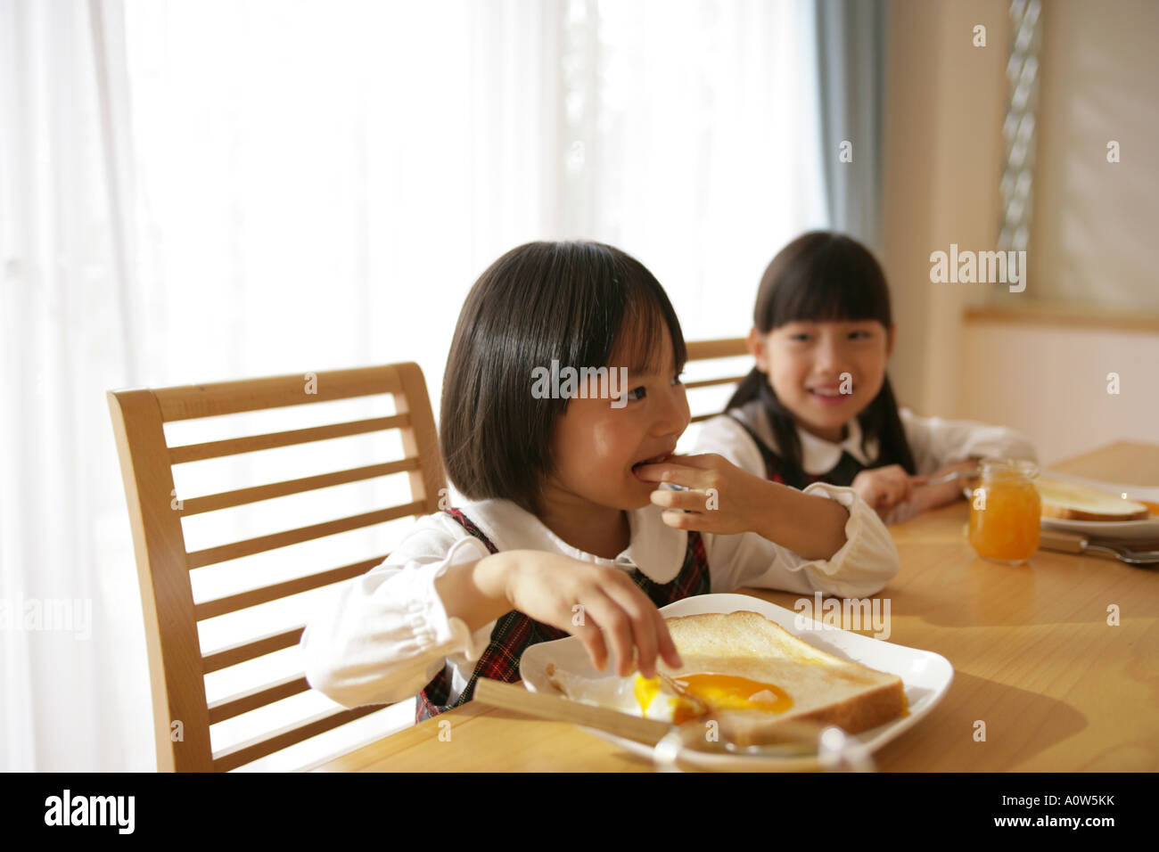 Two girls having breakfast at the dining table Stock Photo - Alamy
