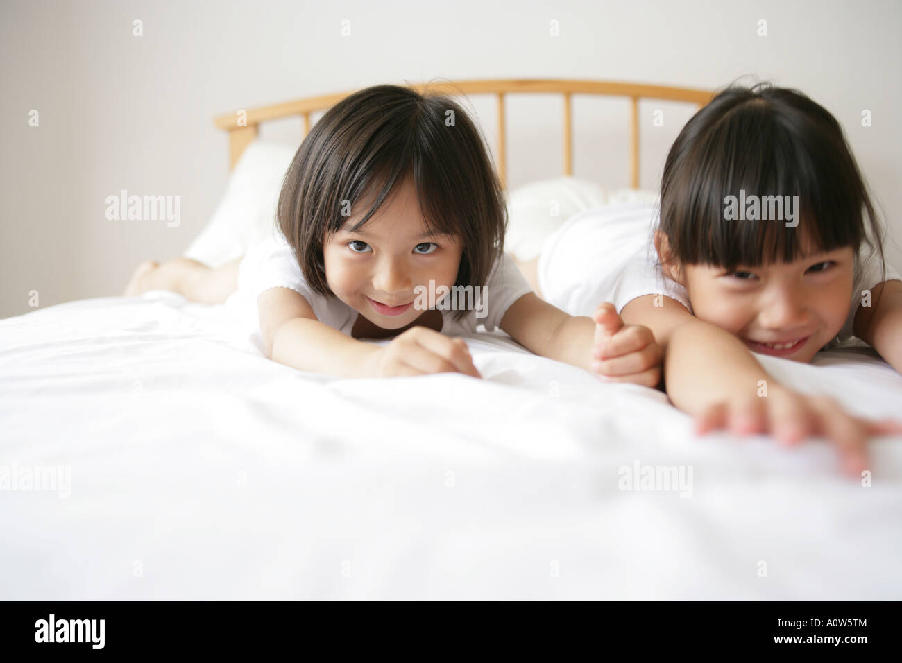 Portrait of a girl with her sister lying on the bed and smiling Stock Photo - Alamy