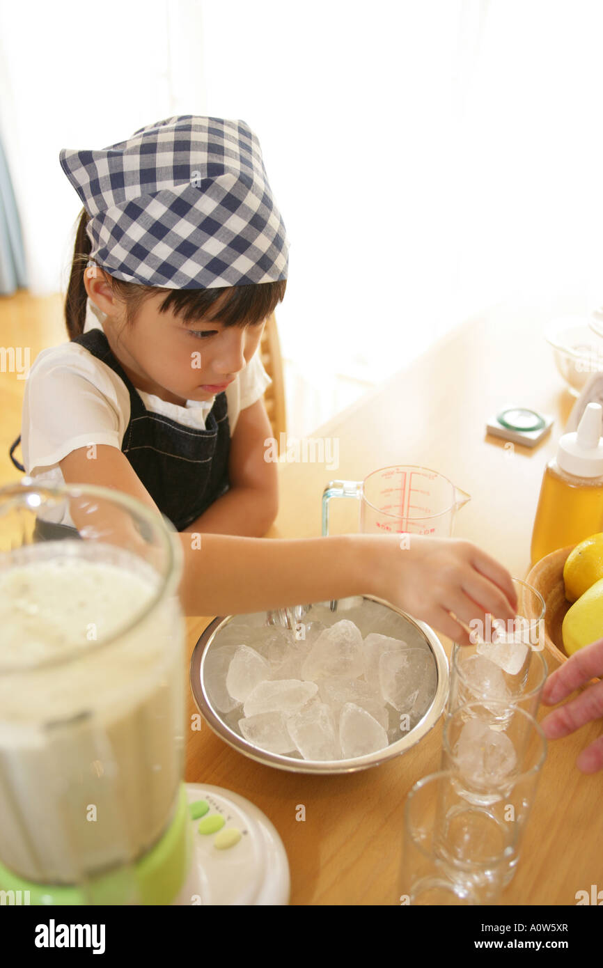 Girl sitting at the table and putting ice in glasses Stock Photo - Alamy
