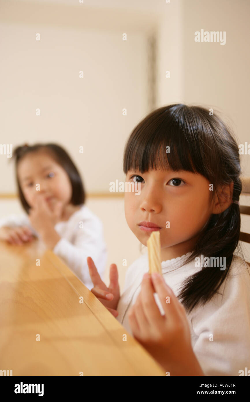 Close up of a girl eating French fries with her sister sitting beside ...