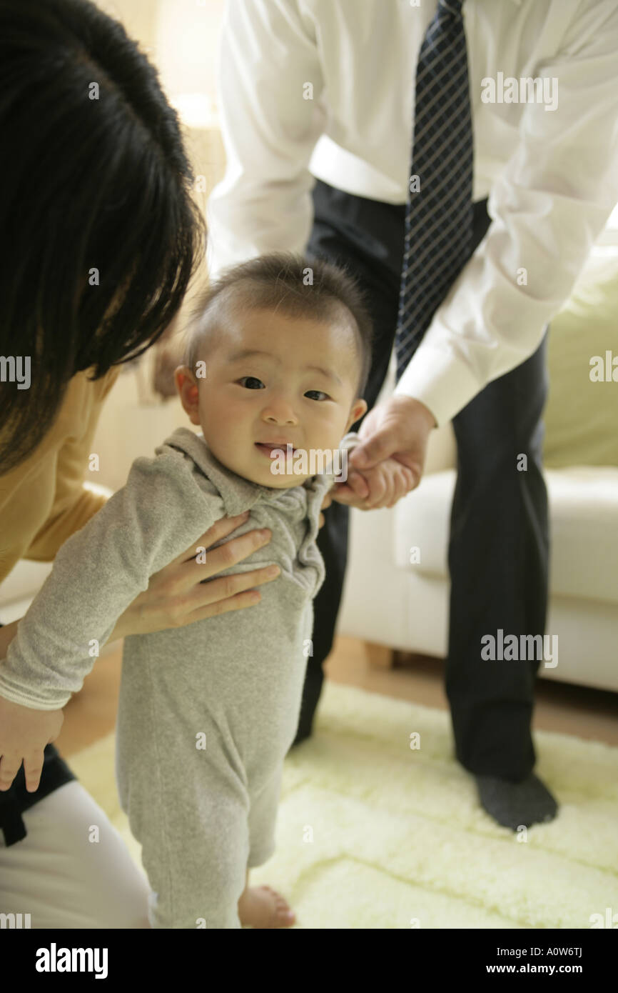 Portrait of a baby boy standing with the help of his parents Stock ...