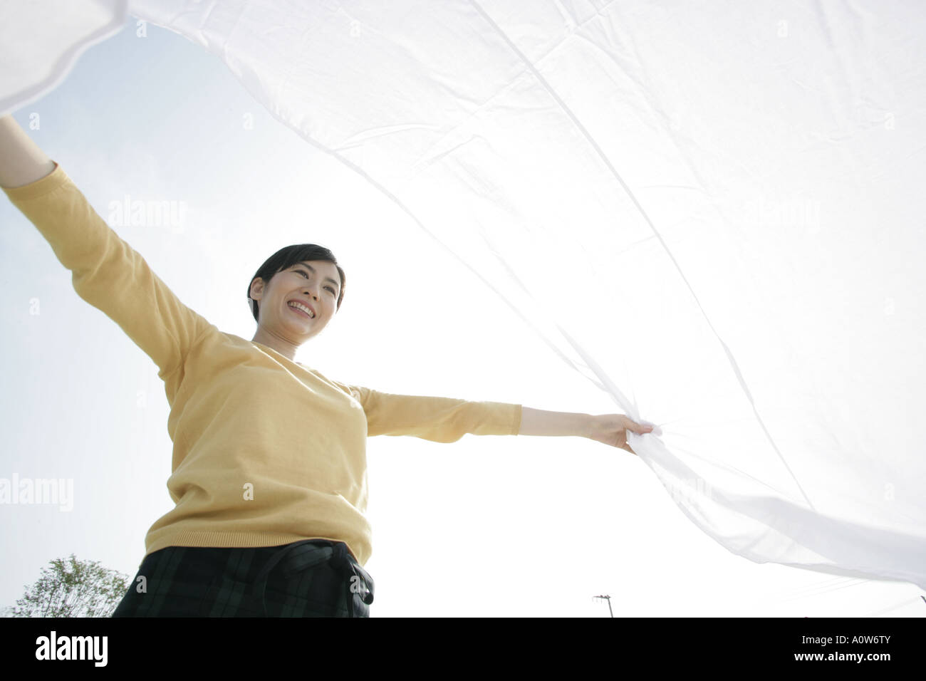 Low angle view of a mid adult woman waving a sheet and smiling Stock ...