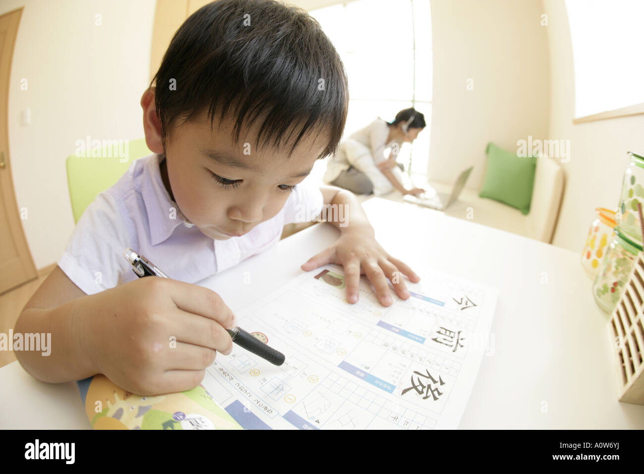 Close up of a boy writing on a sheet of paper with his sister using a ...