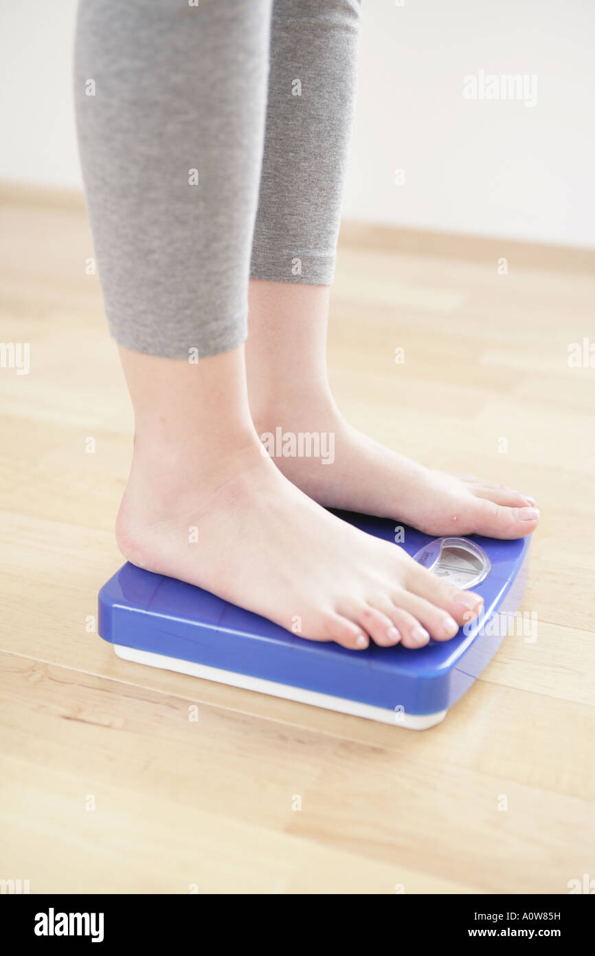 Low section view of a woman standing on a weighing scale Stock Photo ...