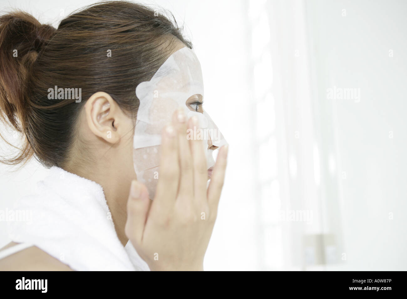 Side profile of a young woman applying a facial mask Stock Photo - Alamy