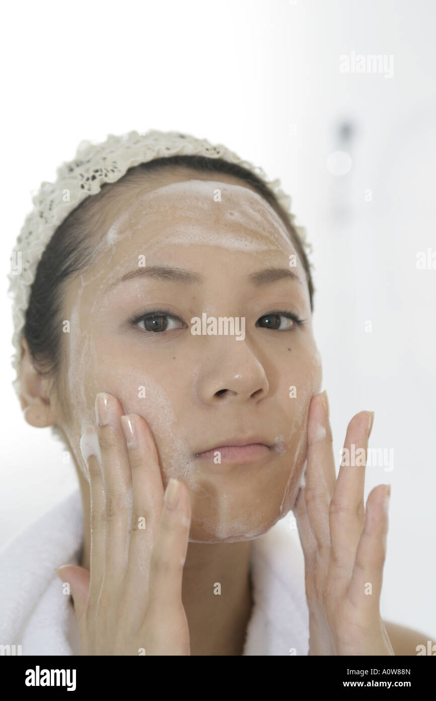 Portrait of a young woman applying soap on her face Stock Photo - Alamy