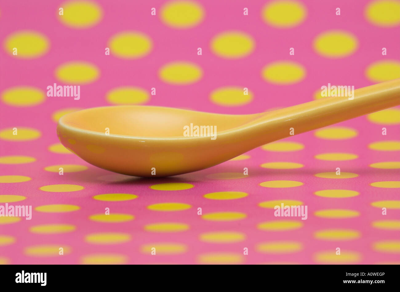 Yellow spoon on pink background Stock Photo - Alamy
