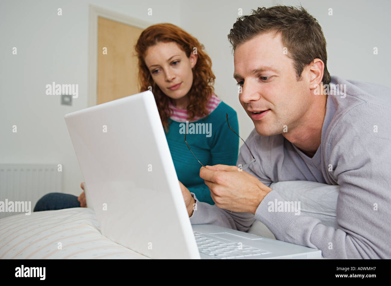 Couple using laptop computer in bedroom Stock Photo - Alamy