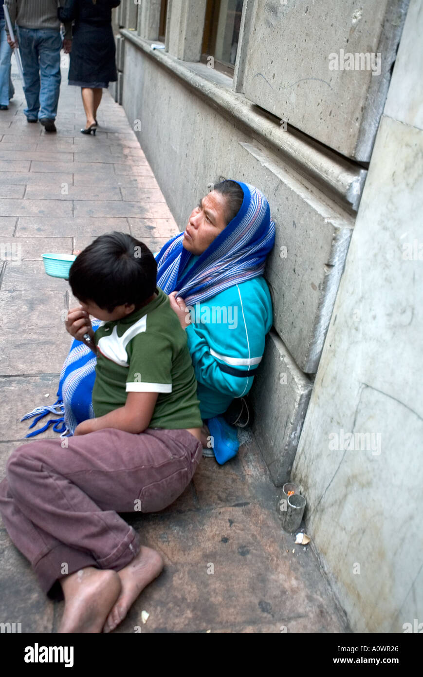 A woman and boy holding out a container begging on the streets of ...