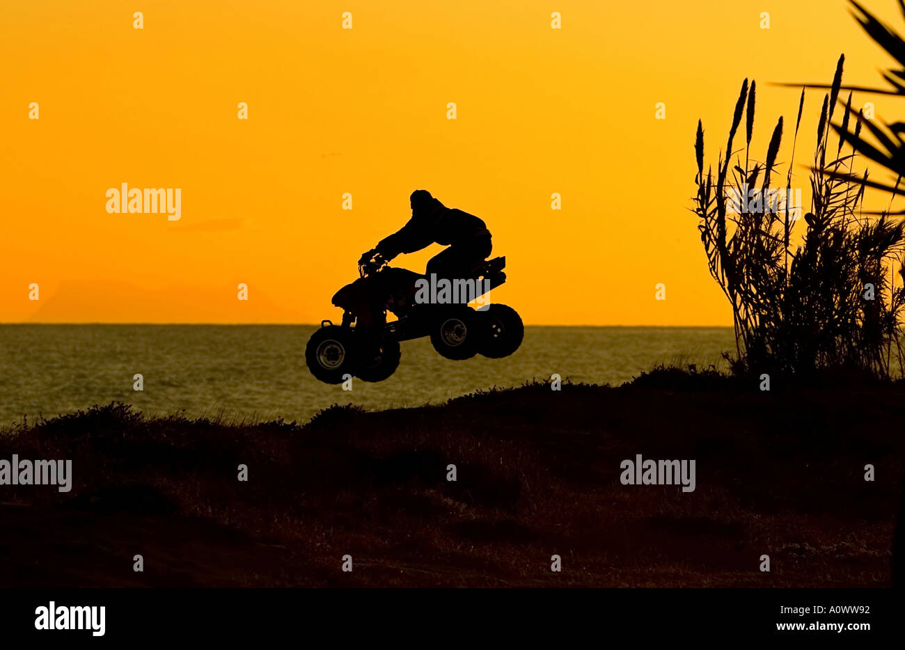 Quad bike jumping on beach at sunset in Spain Stock Photo - Alamy