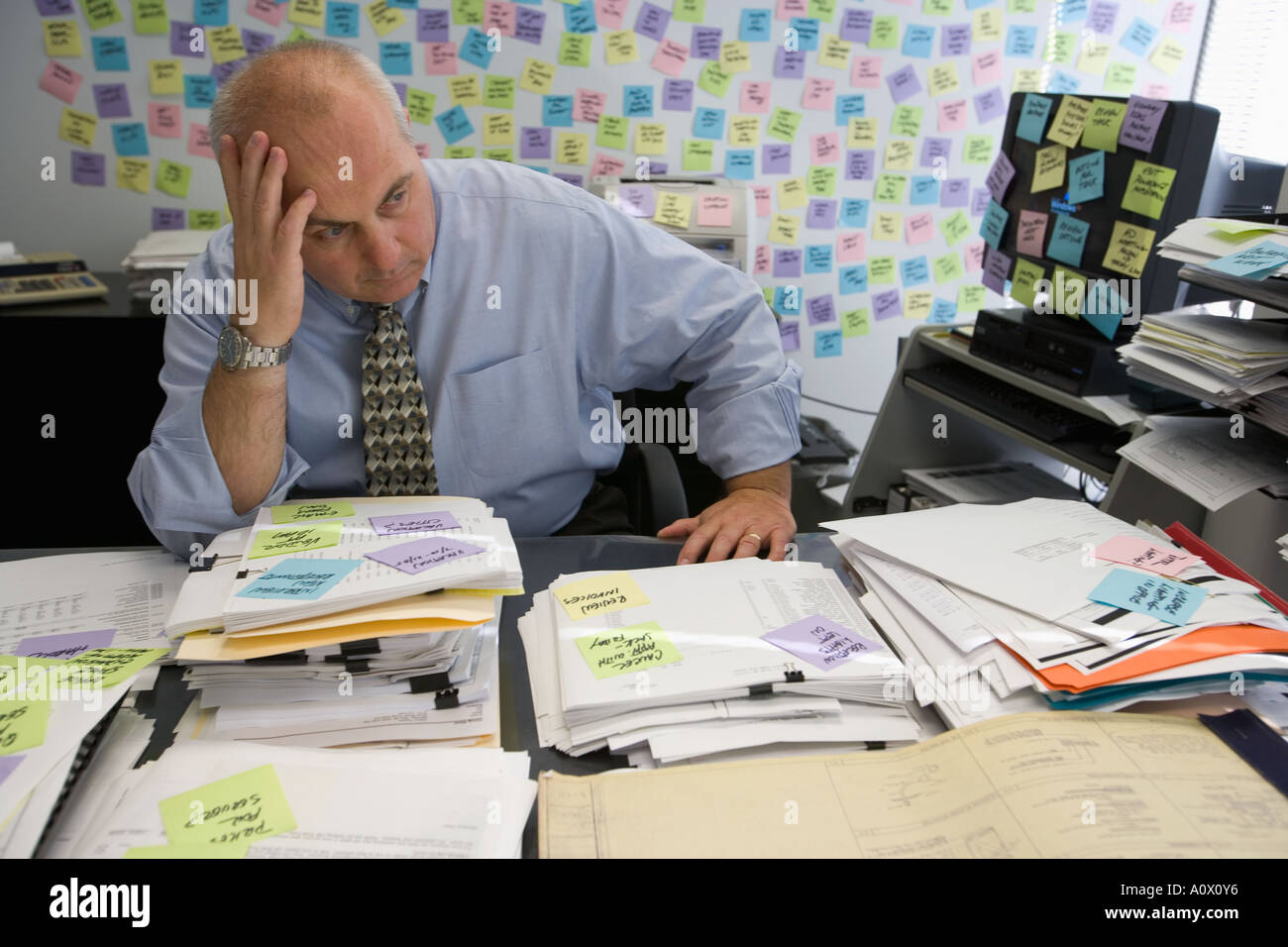 Stressed executive is surrounded by sticky notes and paperwork Stock ...