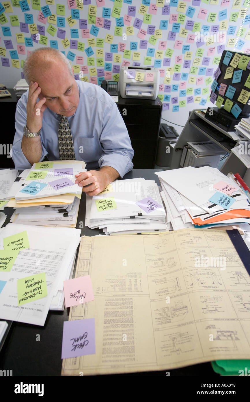 overworked office worker executive ponders at paperwork and workload ...