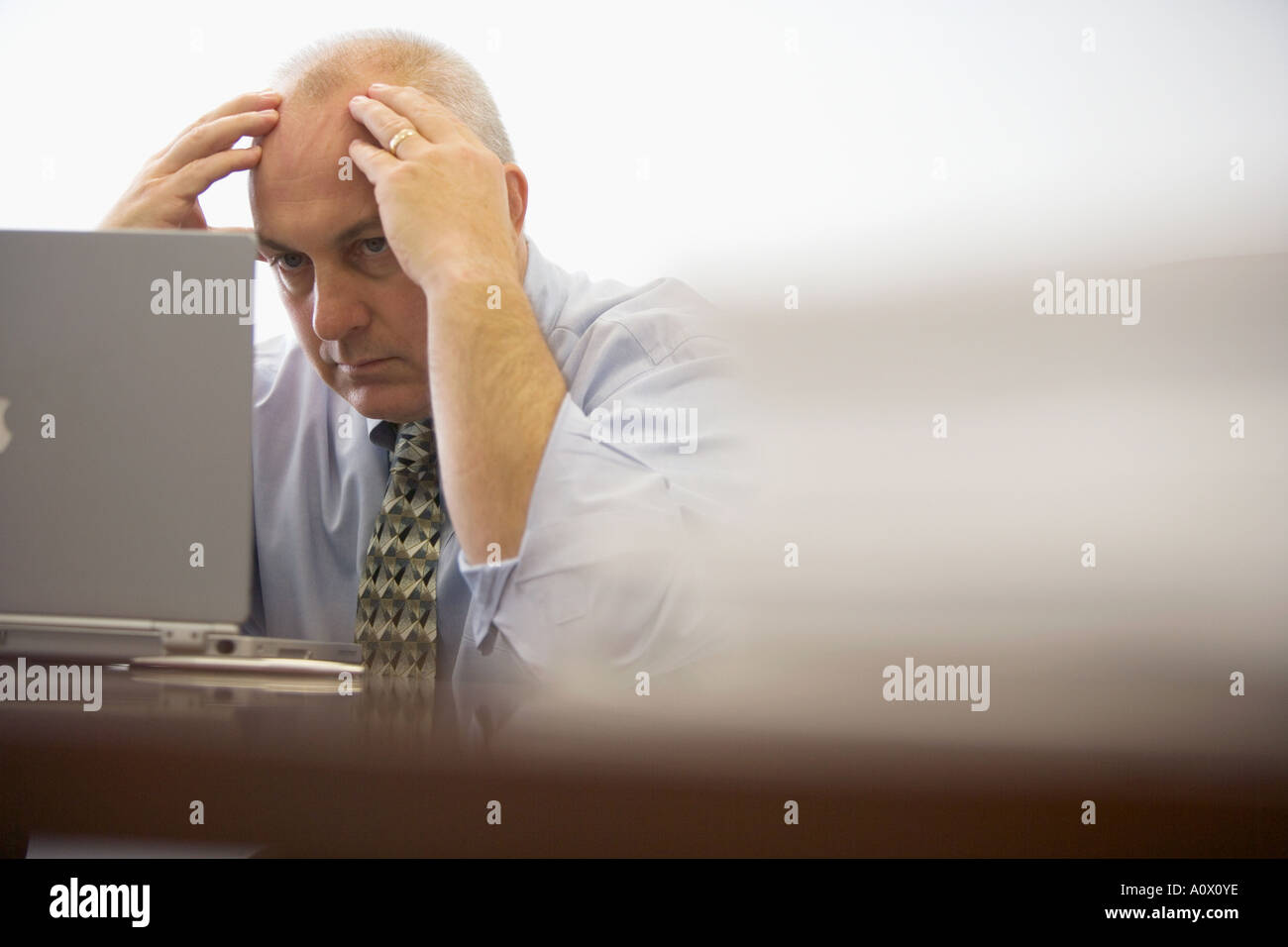 Stressed business executive working on portable computer in office ...