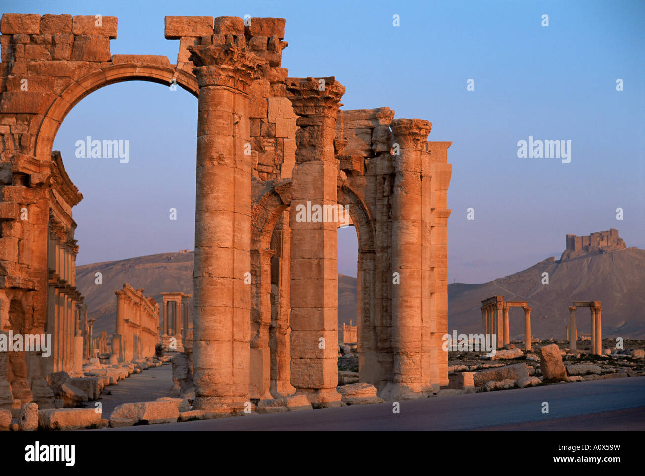 Monumental arch at archaeological site with Arab castle beyond Palmyra ...