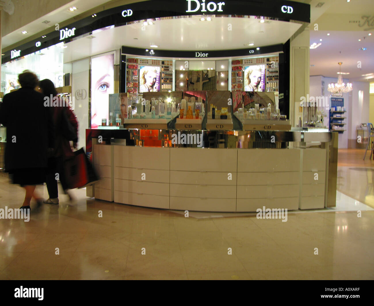 women with shopping bags walking past the dior perfume counter in a ...