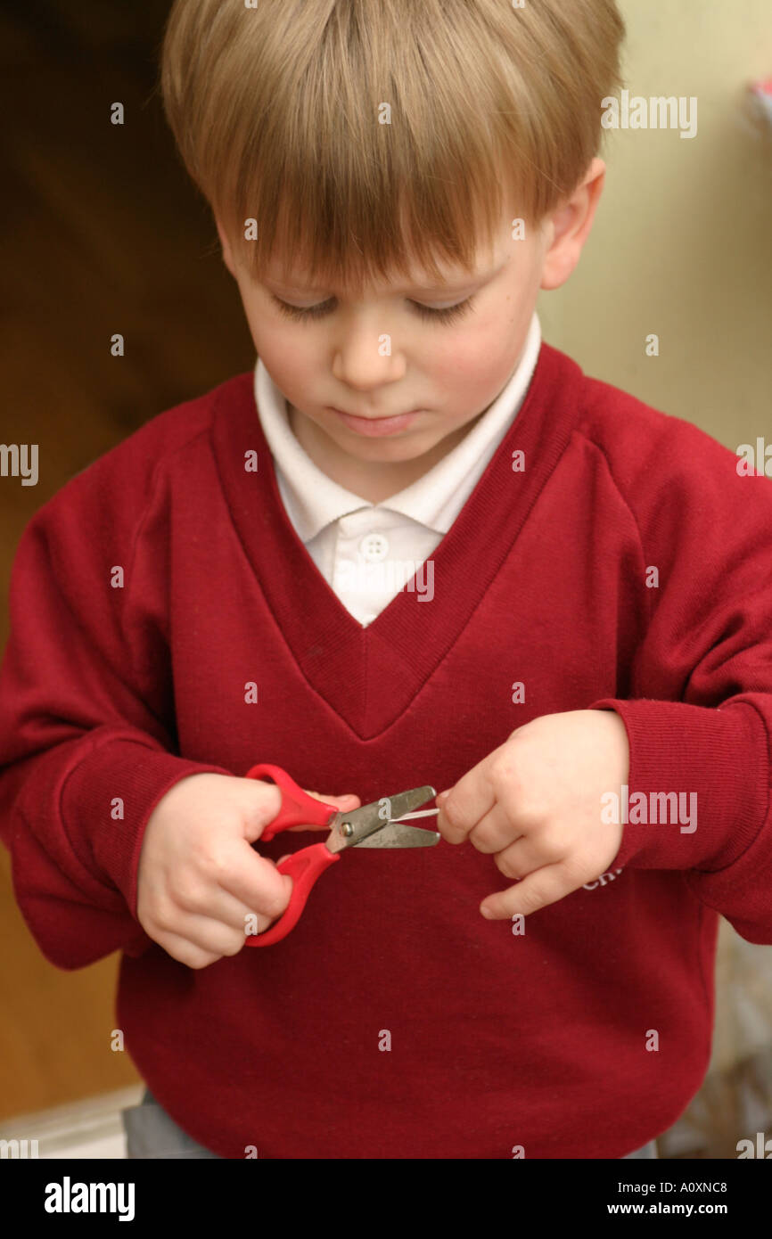 Four year old boy in school uniform plays with scissors Stock Photo - Alamy
