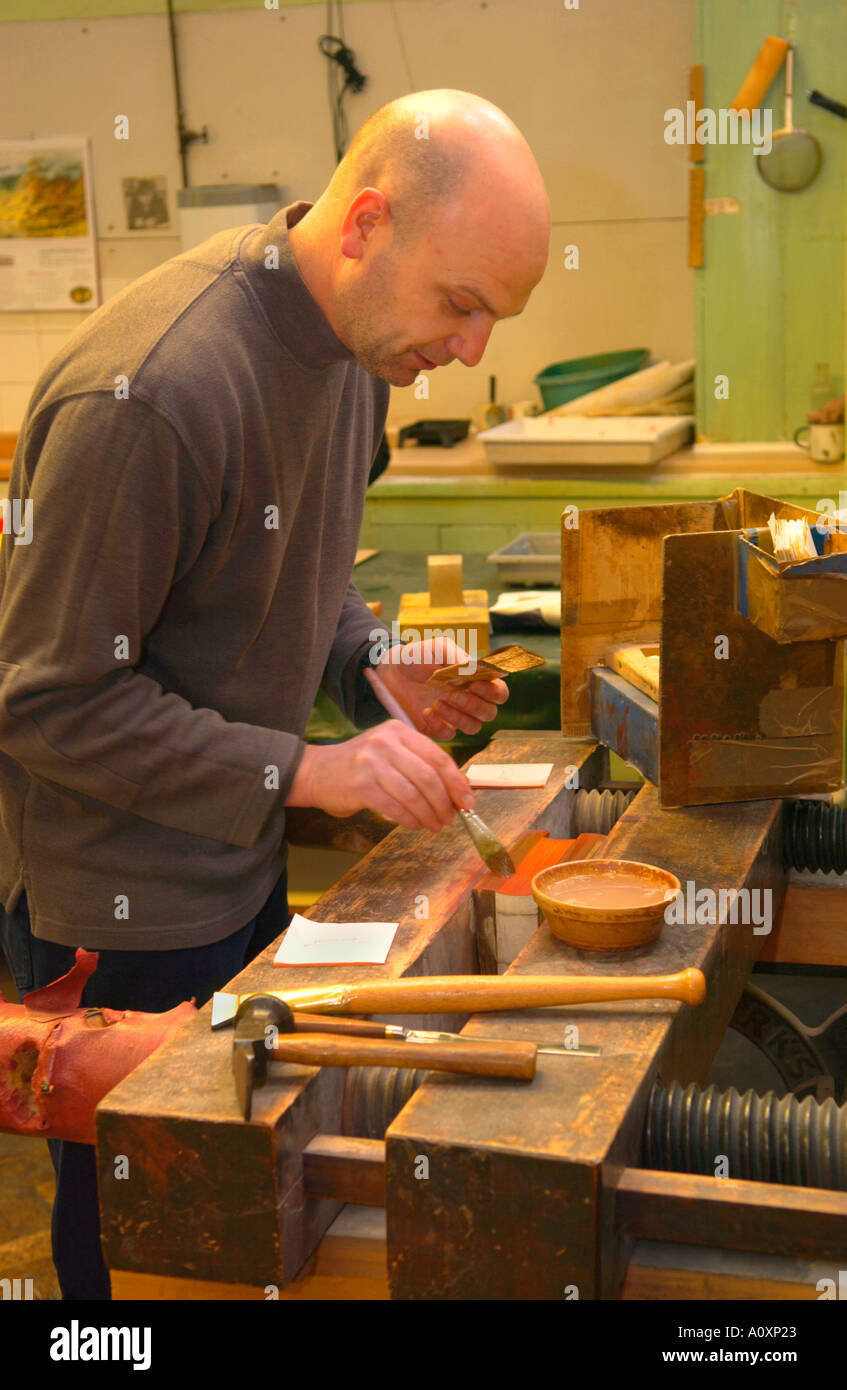 Craftsman guilding the page edges of a book at the George Bayntun book ...