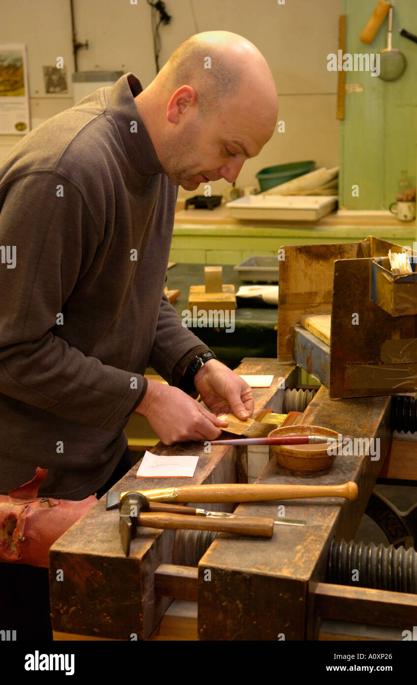 Craftsman guilding the page edges of a book at the George Bayntun book ...