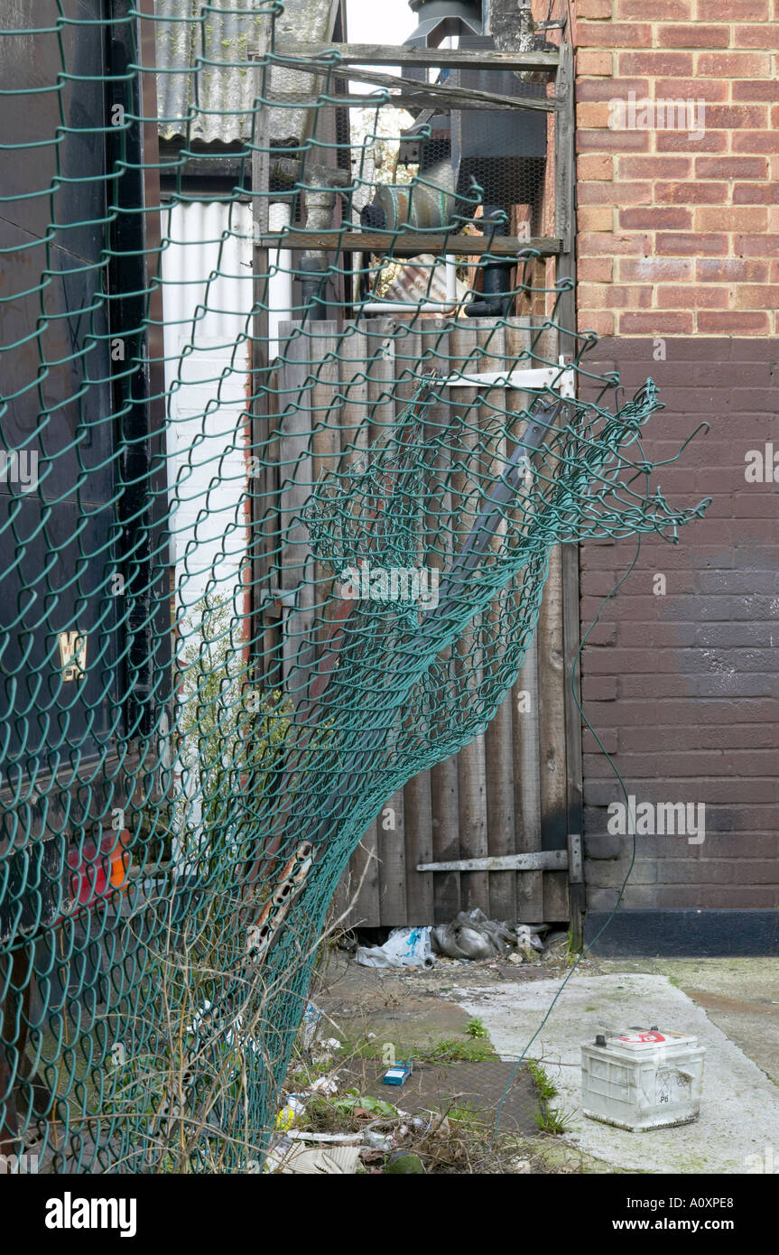 Urban Living, damaged chain link fence and battery Stock Photo - Alamy